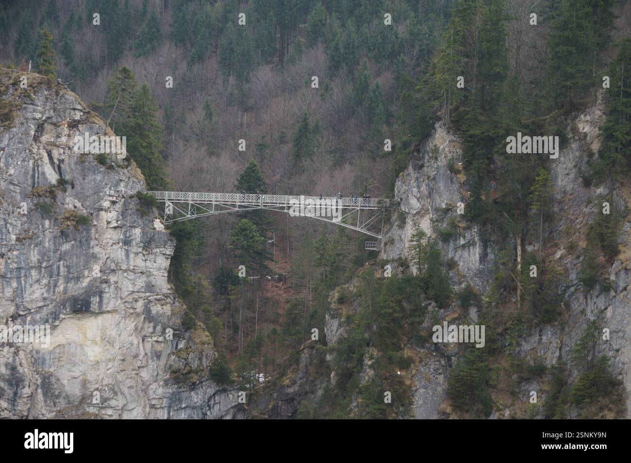 A weathered wooden bridge stretches precariously across a deep chasm ...