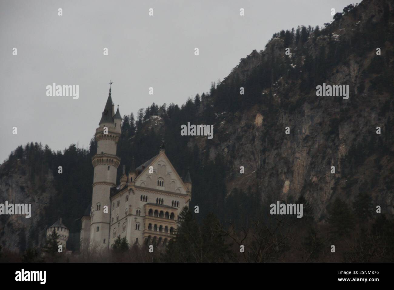 A white castle with a tall tower sits atop a snow-capped mountain in ...