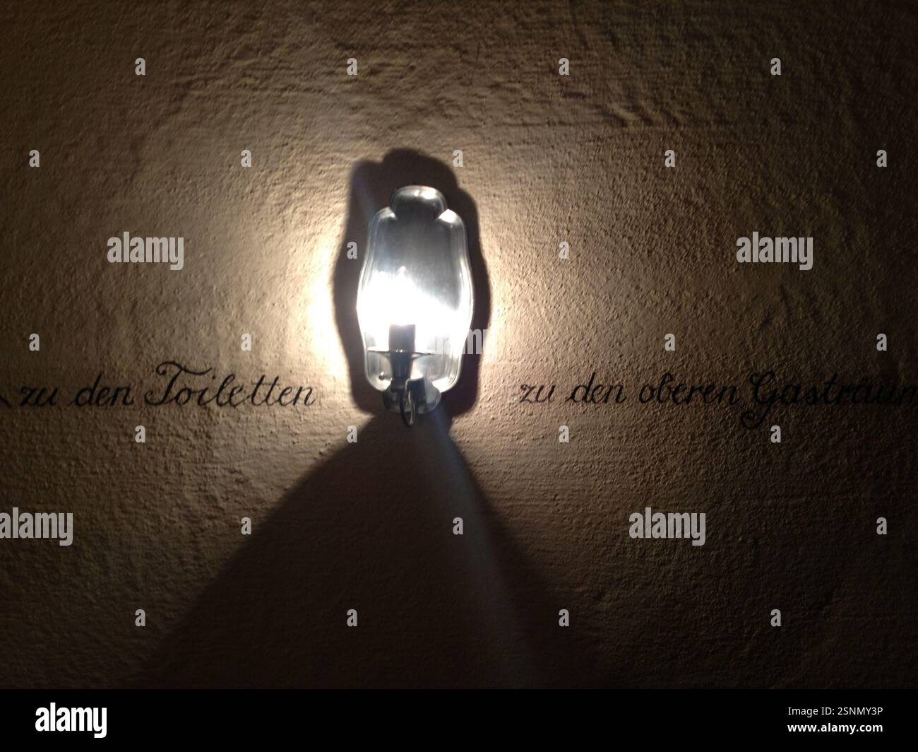 Wall-mounted light illuminates handwritten signs pointing to toilets ...