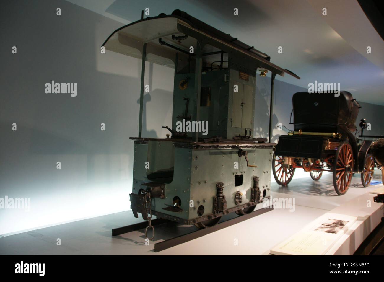 A vintage horse-drawn carriage stands beside a steam locomotive in a ...
