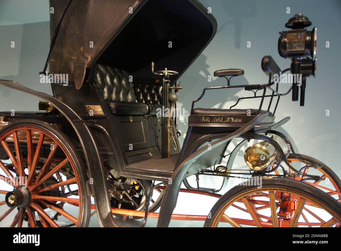 A black antique carriage with wooden wheels and a lantern on the front ...