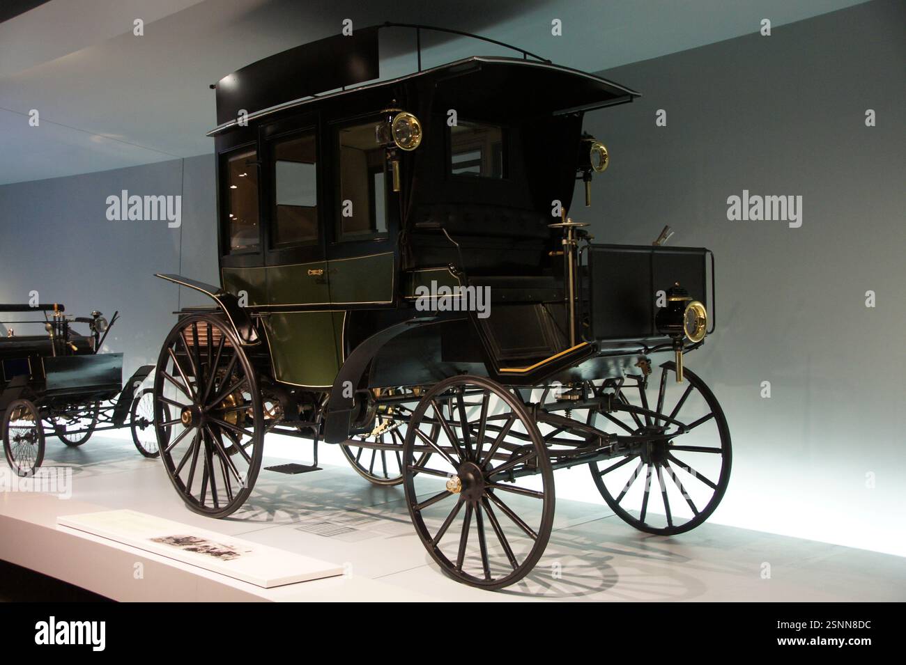 A black, ornately carved horse-drawn carriage from the early 20th ...