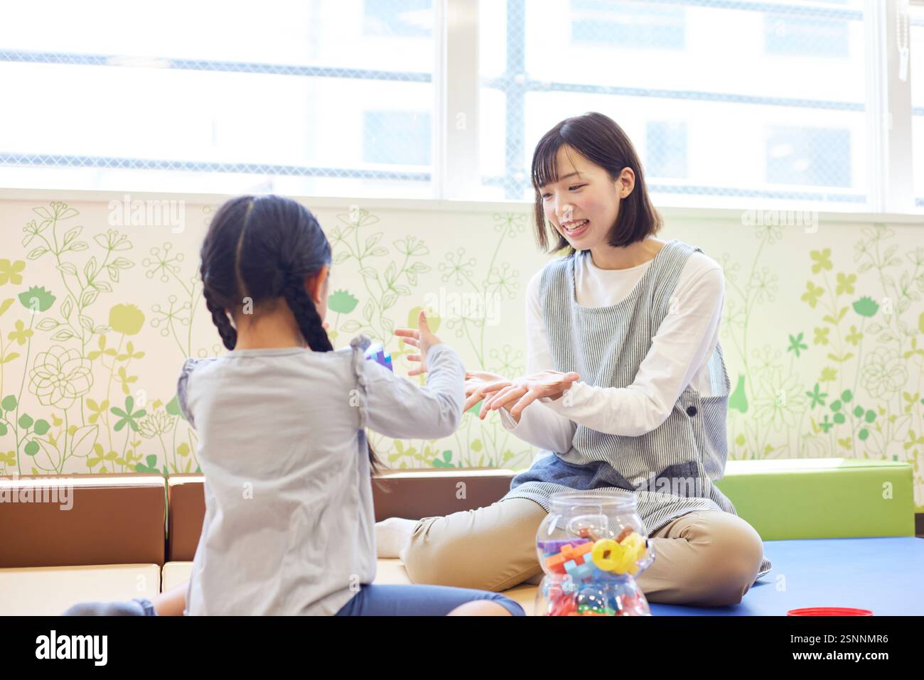 Childcare worker woman playing with children with toys in day-care ...