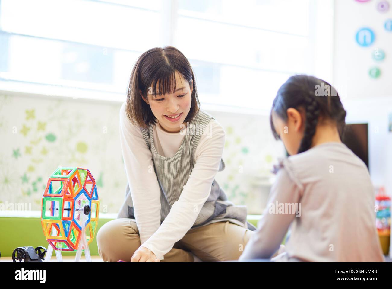 Childcare worker woman playing with children with toys in day-care ...