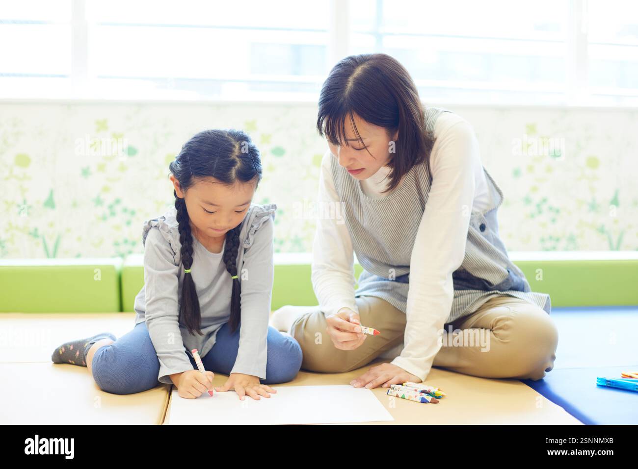 Female teacher who draws with preschool children at a nursery school ...