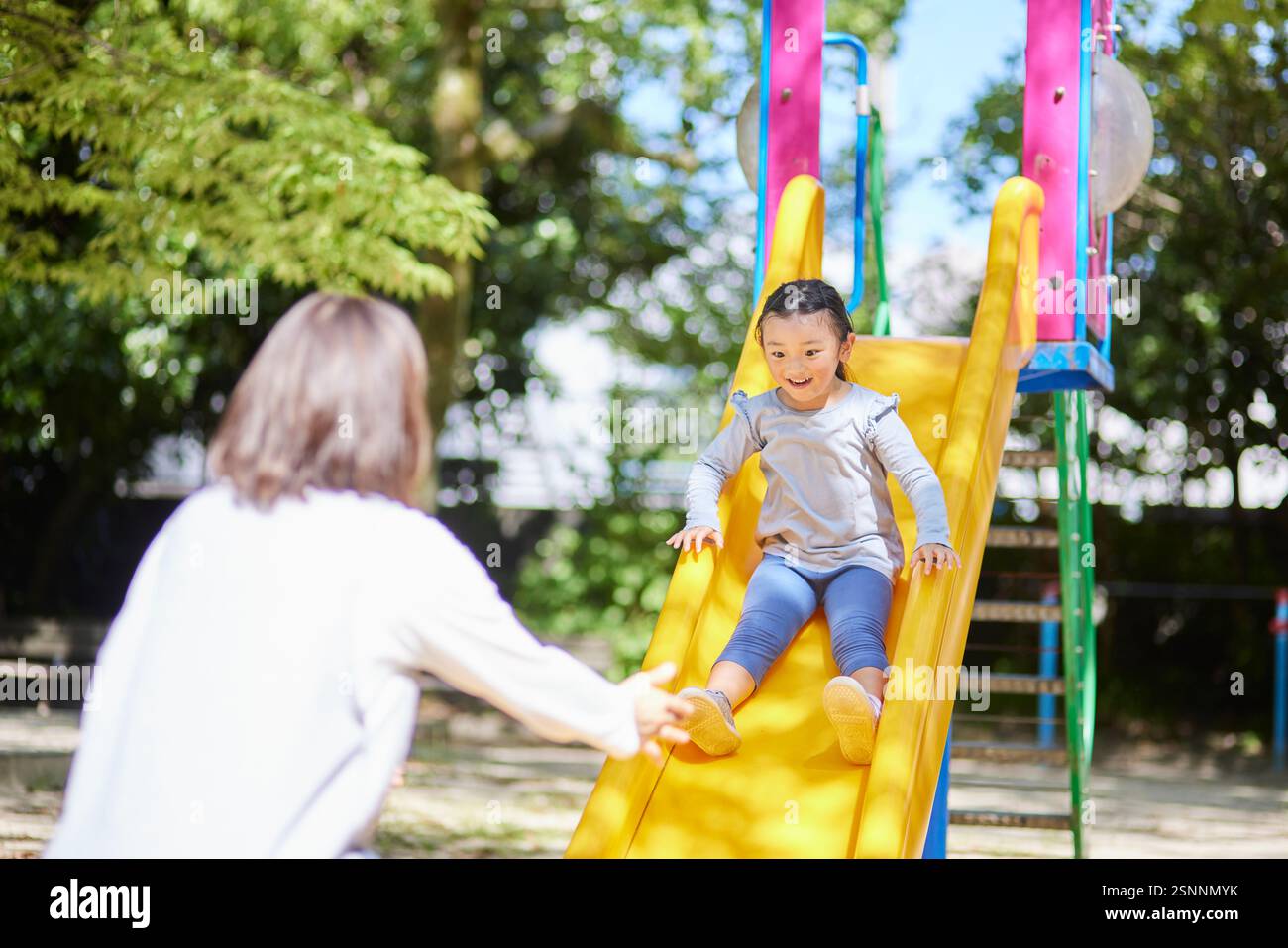 Childcare worker woman looking after child with child playing on slide ...