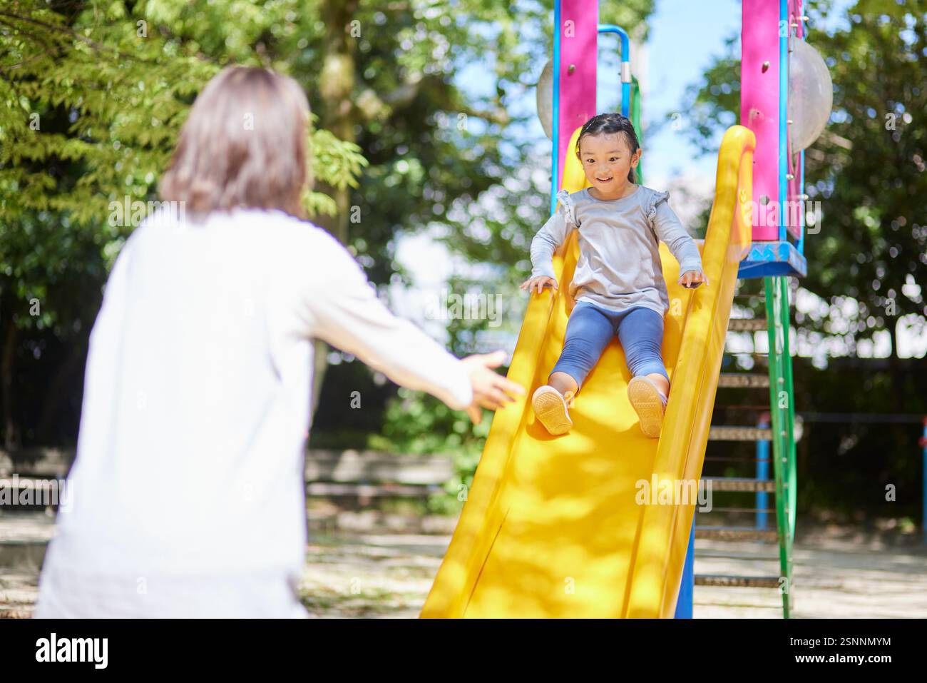 Childcare worker woman looking after child with child playing on slide ...