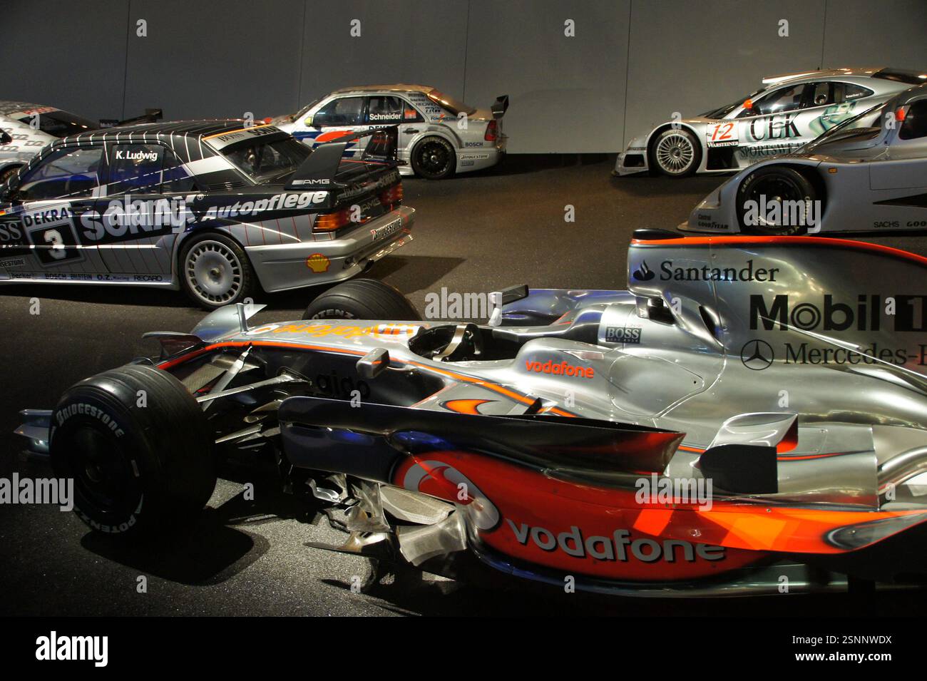 A metallic silver Formula 1 race car with orange accents gleams in a ...