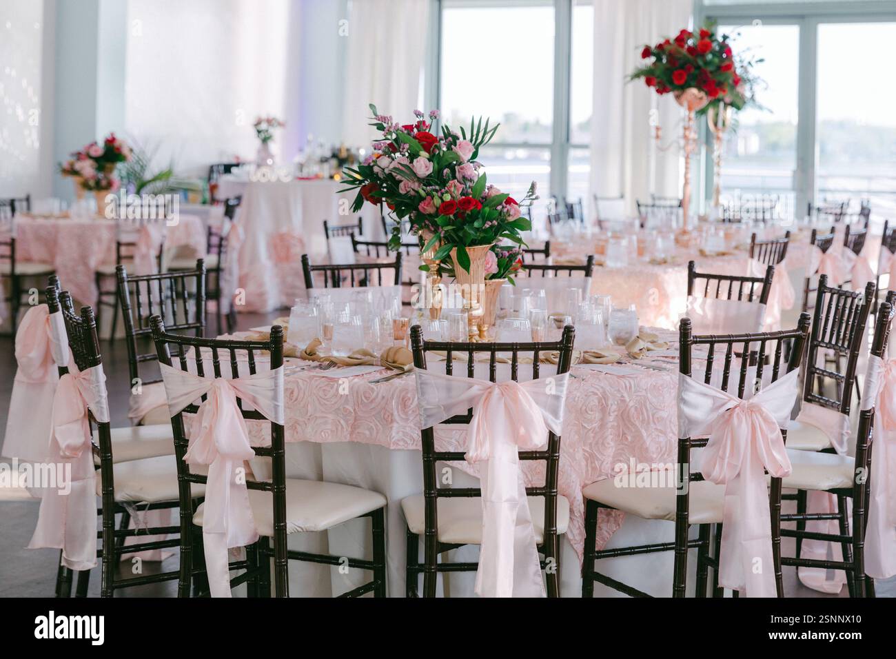 Tables adorned with pink details and floral arrangements create a ...