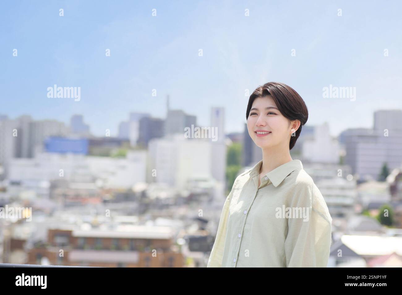 Smiling young woman standing on rooftop Stock Photo - Alamy