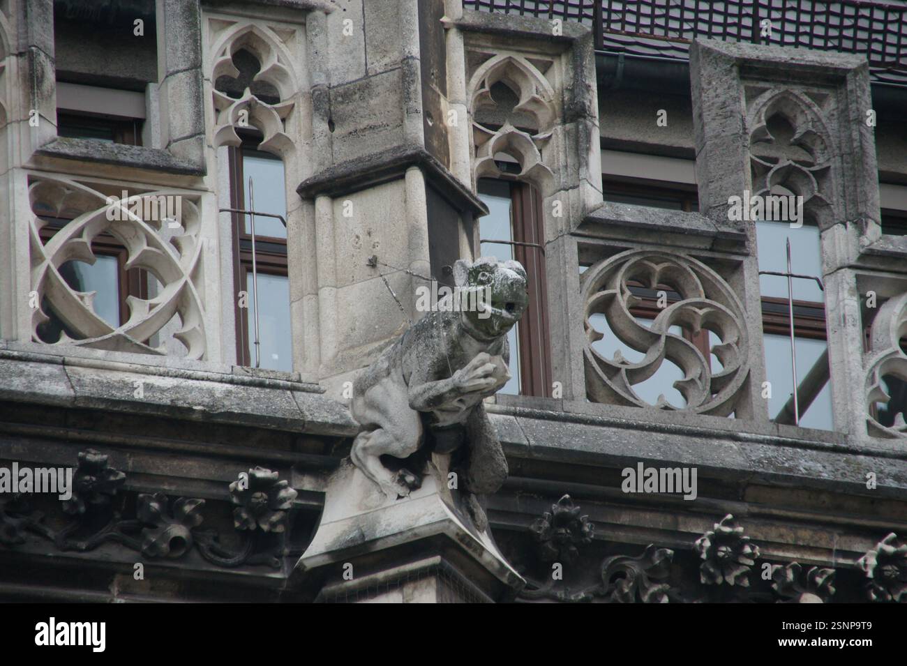 An ornate stone gargoyle with an open mouth perches on a building in ...