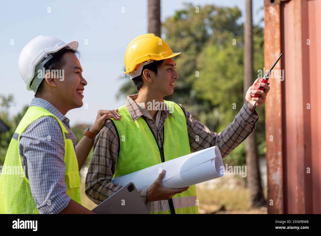 Engineers collaborating on construction plans outdoors with blueprints ...