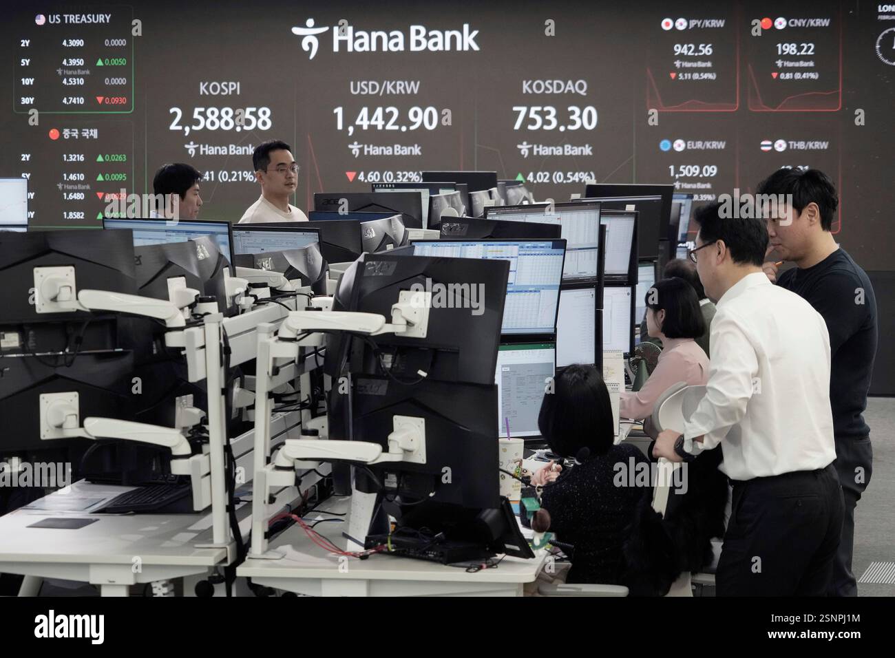 Currency traders watch monitors near a screen showing the Korea ...