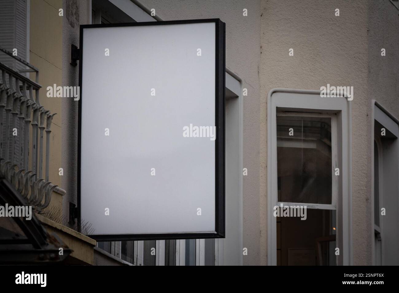 An empty white rectangular sign hangs outside a German store, offering ...