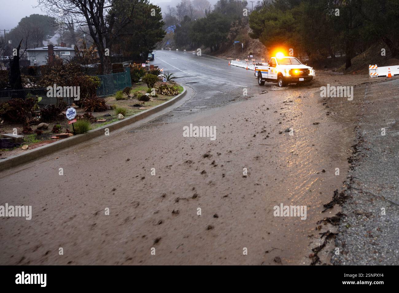 Mud flows down a road in the Eaton Fire zone during a storm Thursday ...