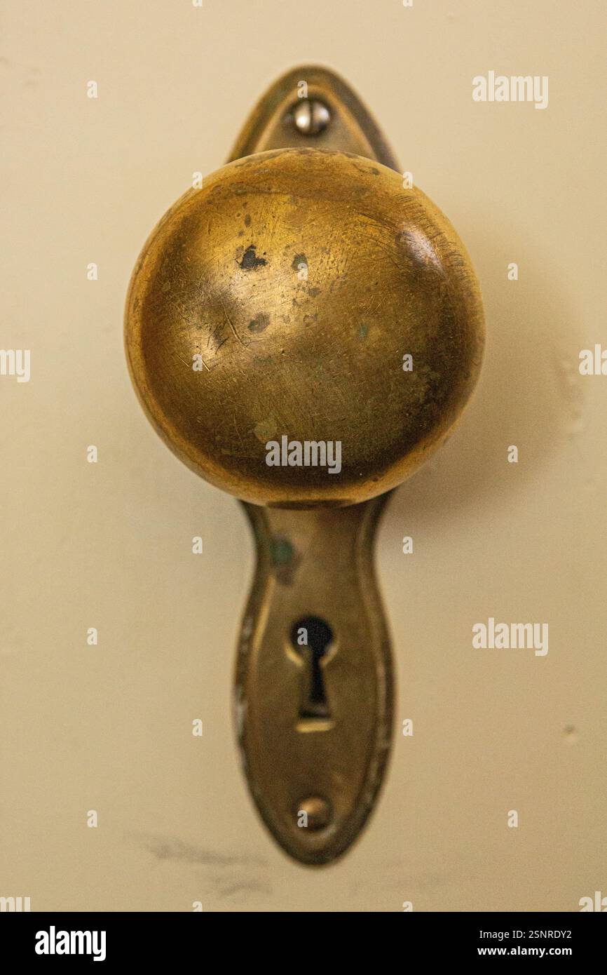 An antique brass doorknob with a skeleton key lock. on an interior door ...