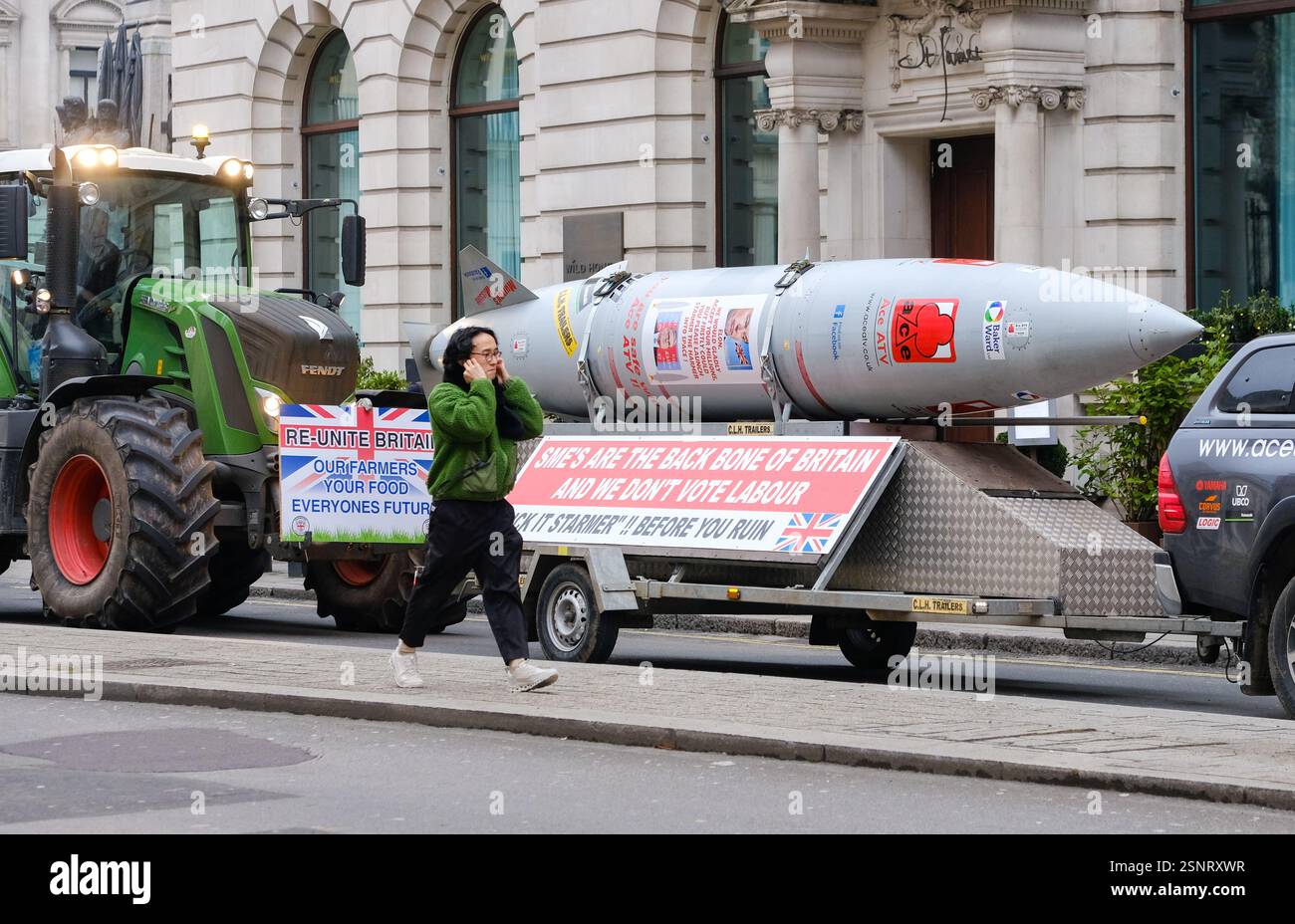 A man covers his ears as he passes a rocket and hundreds of tractors ...