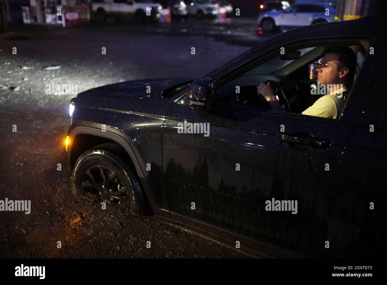 A motorist drives through a mud-covered road in the Palisades Fire zone ...