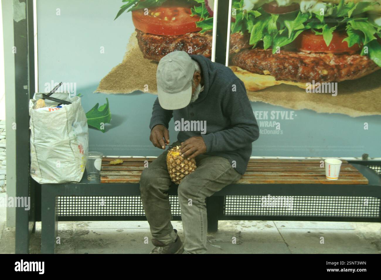 Bucharest, Romania. Elderly homeless man in a bus station cutting open ...