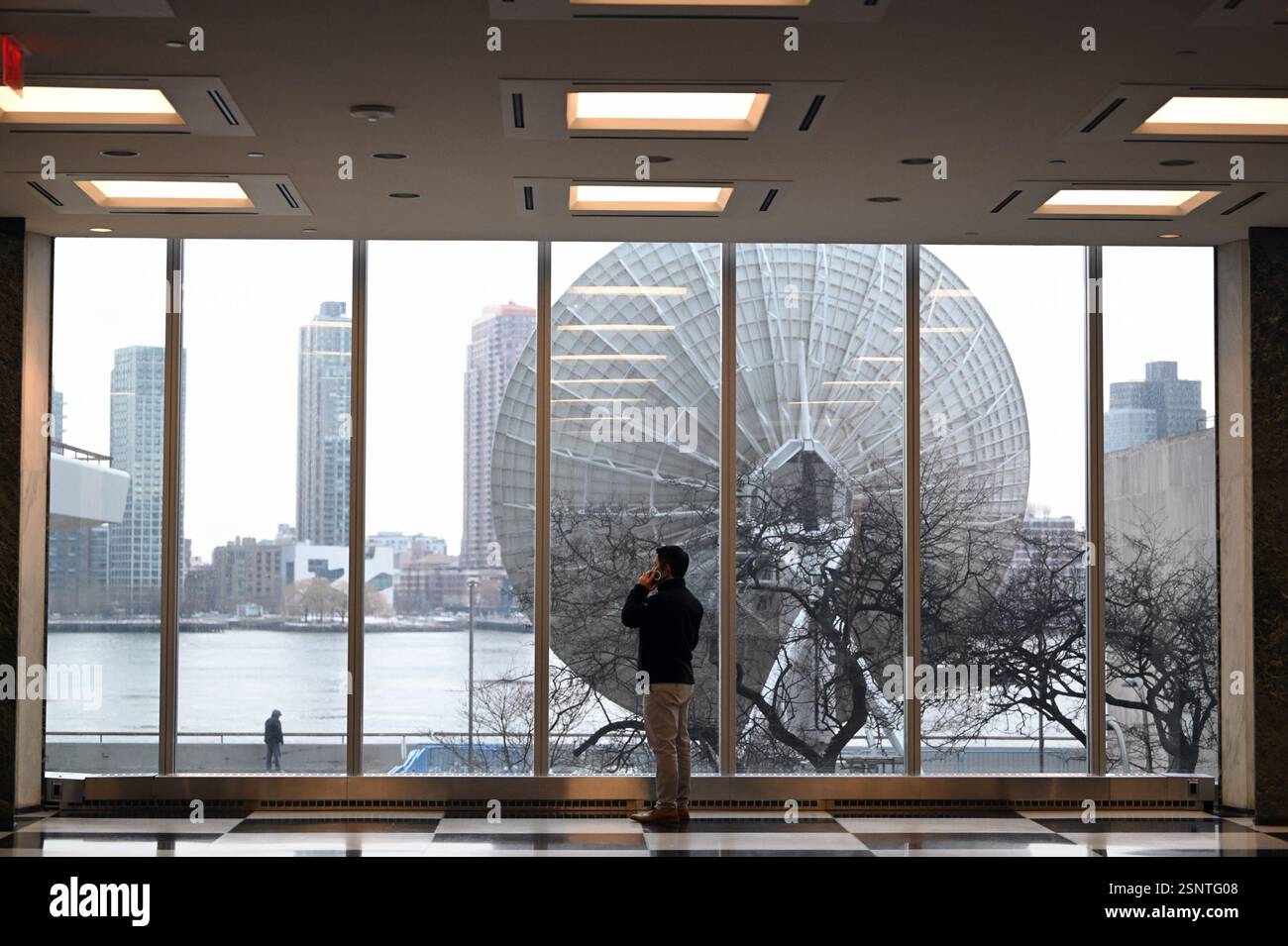 New York, USA. 13th Feb, 2025. A man stands at a window with a view of ...