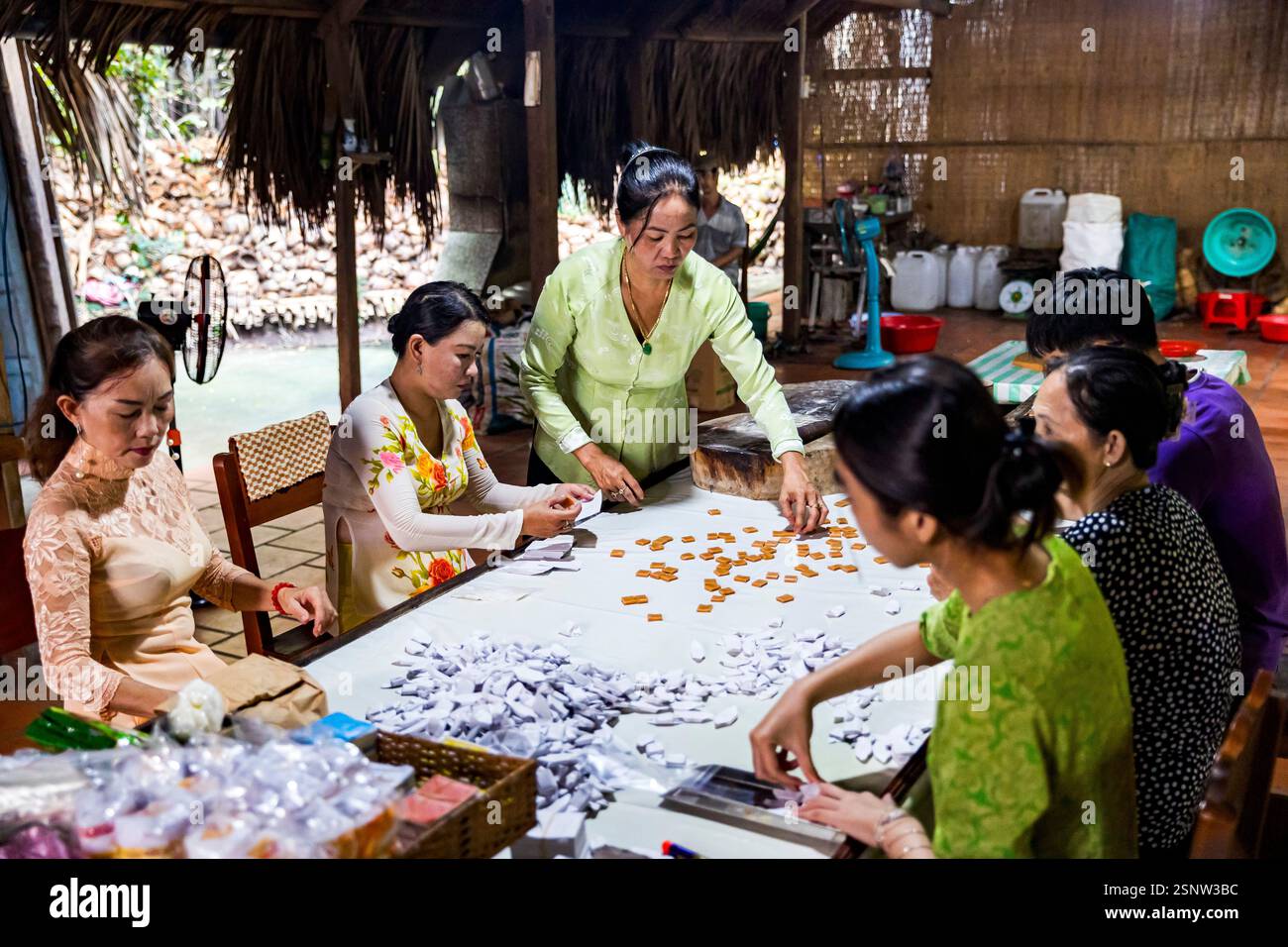 A group of workers focus on preparing traditional packs of coconut ...