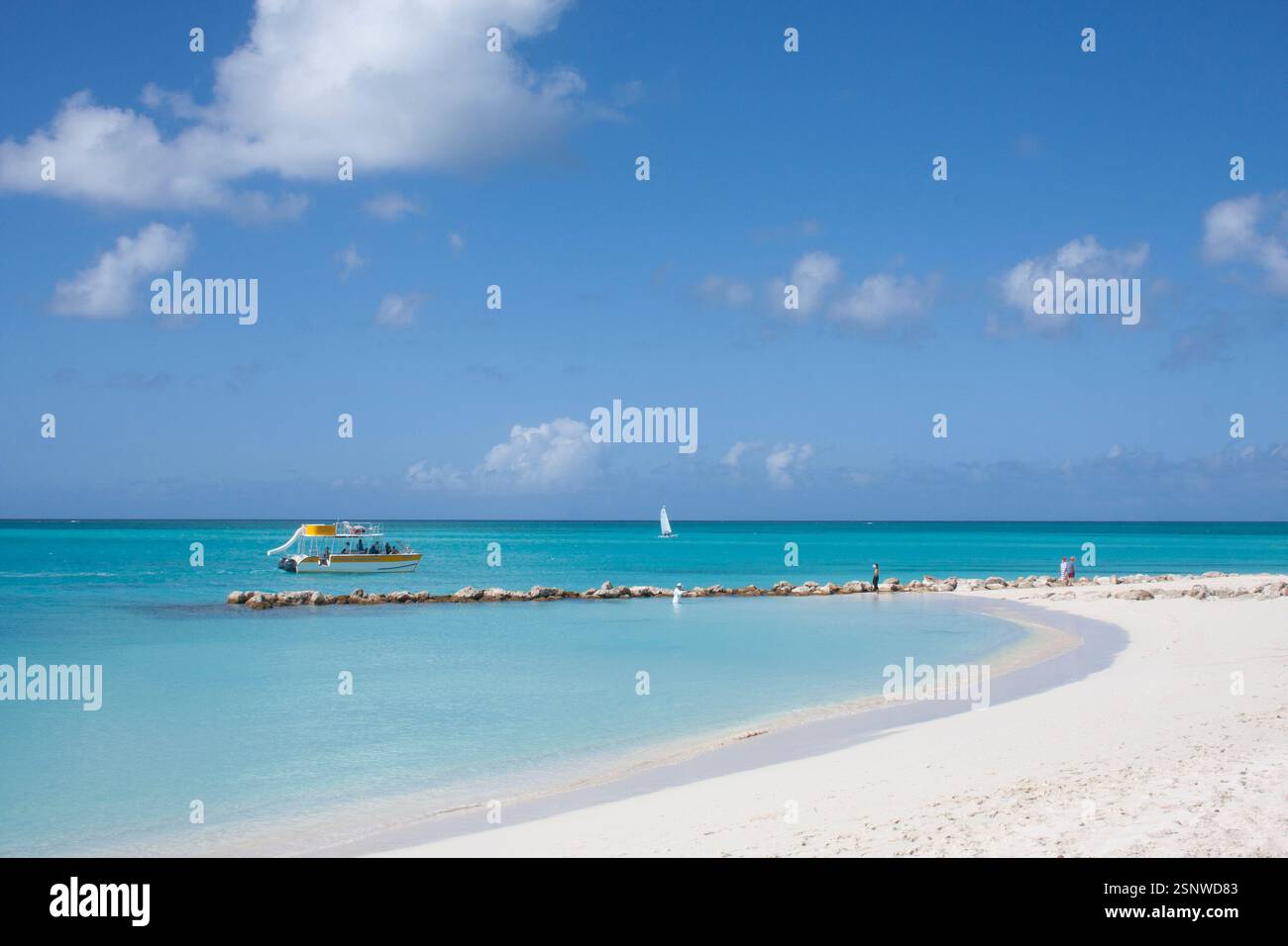 A tour boat cruises by a breakwater along Grace Bay beach in Turks and ...