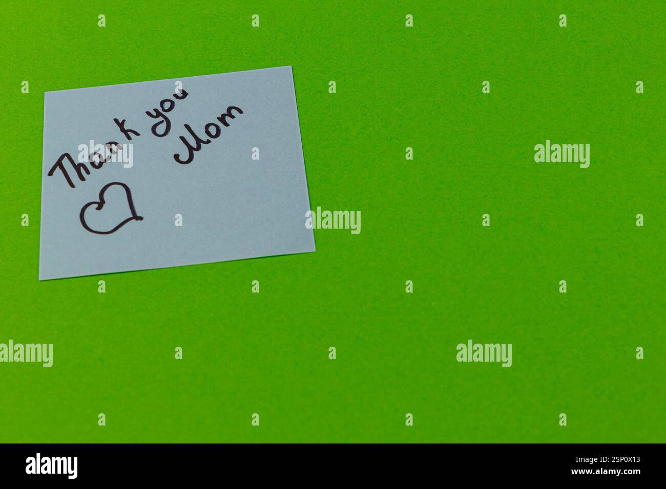 A handwritten note placed on a bright green surface expresses love and ...