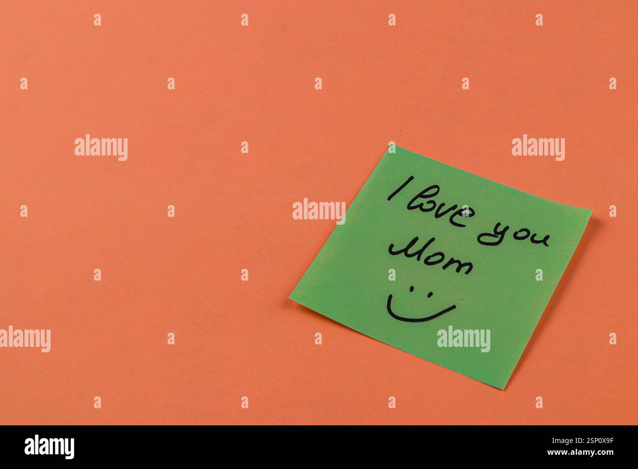 A green sticky note is placed on a bright orange surface, expressing ...