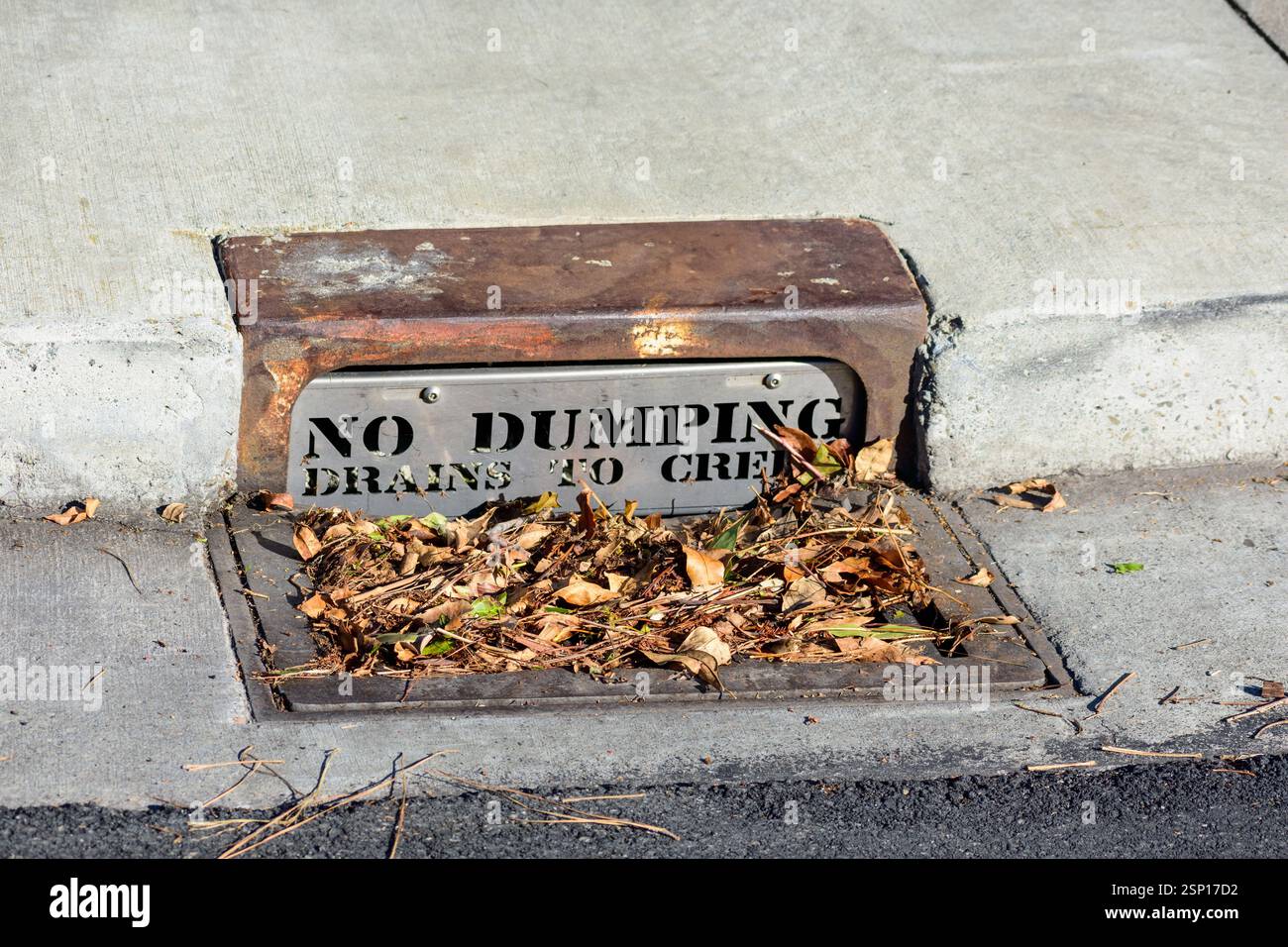 A rusted storm drain grate marked No Dumping, Drains to Creek ...