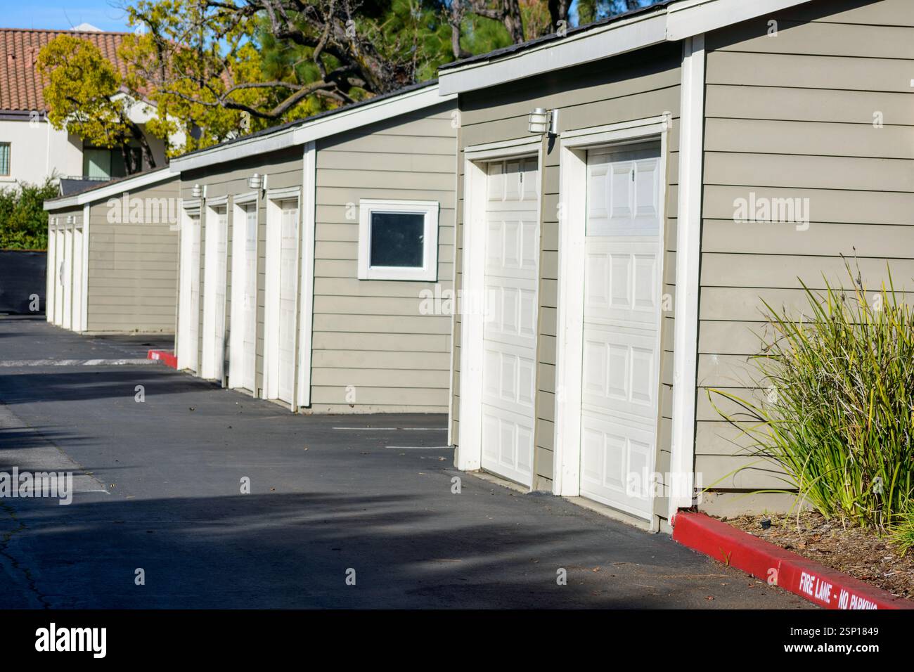 A row of beige residential garage units with white doors and a small ...
