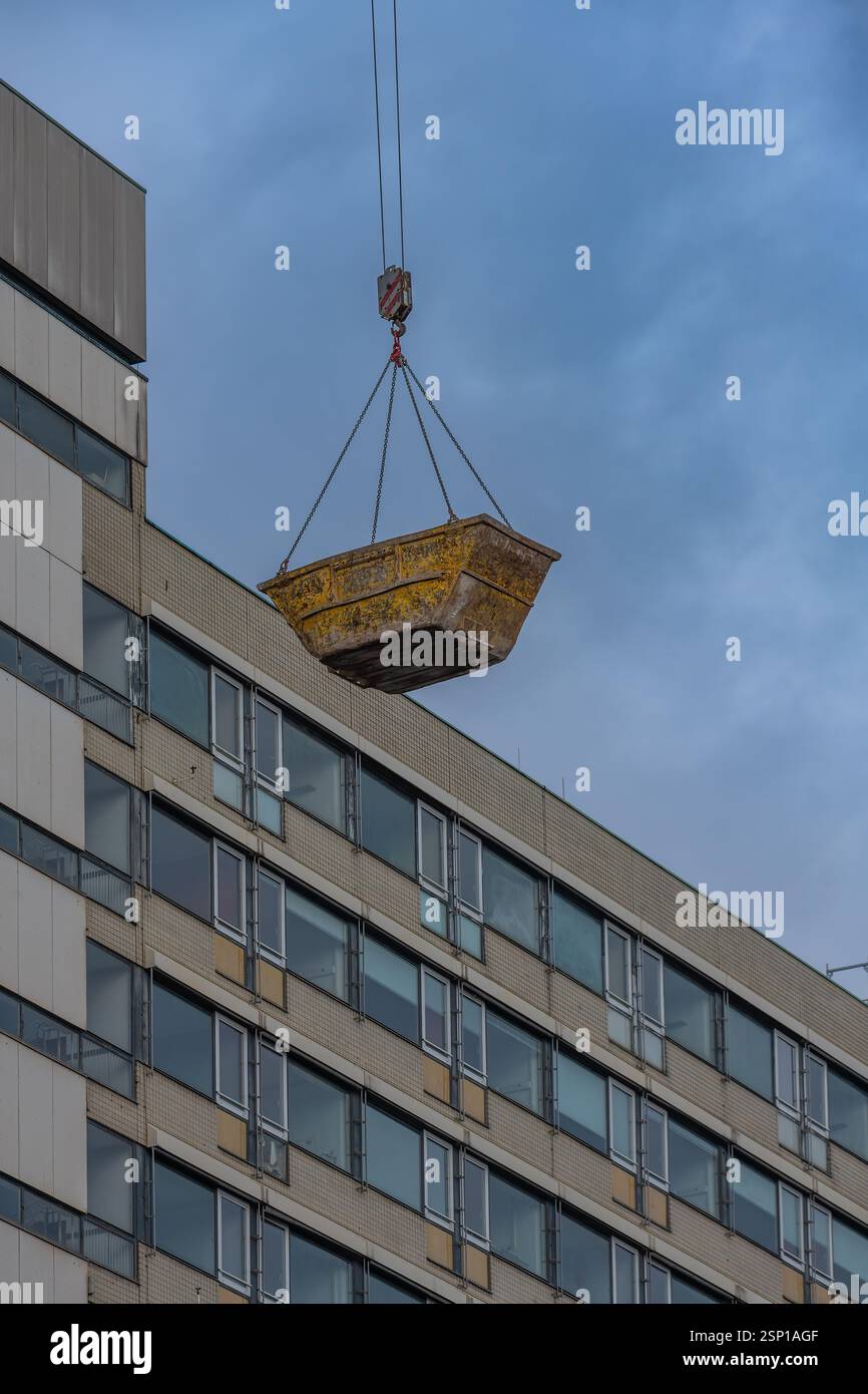 Yellow old skip bin hanging on chains Stock Photo - Alamy