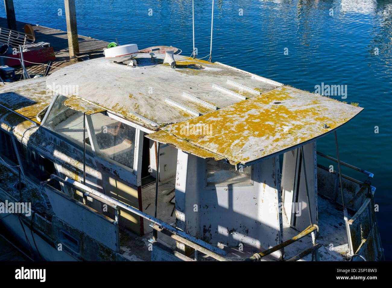 A neglected, moss-covered boat with a deteriorated roof and rusting ...
