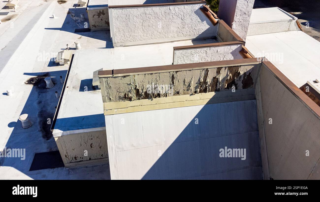 Aerial view of a flat rooftop with peeling walls, weather damage, and ...