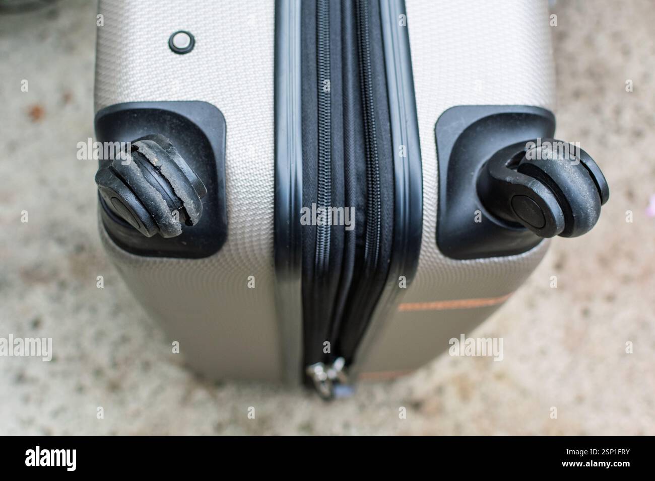 Damaged cracked suitcase wheel and another intact wheel on a hard shell ...