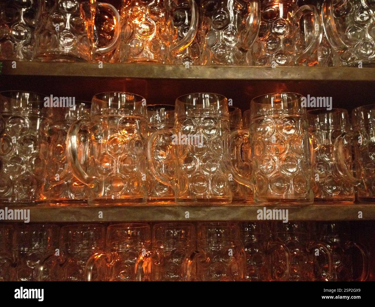 Glass beer steins with handles, illuminated from behind, arranged on ...