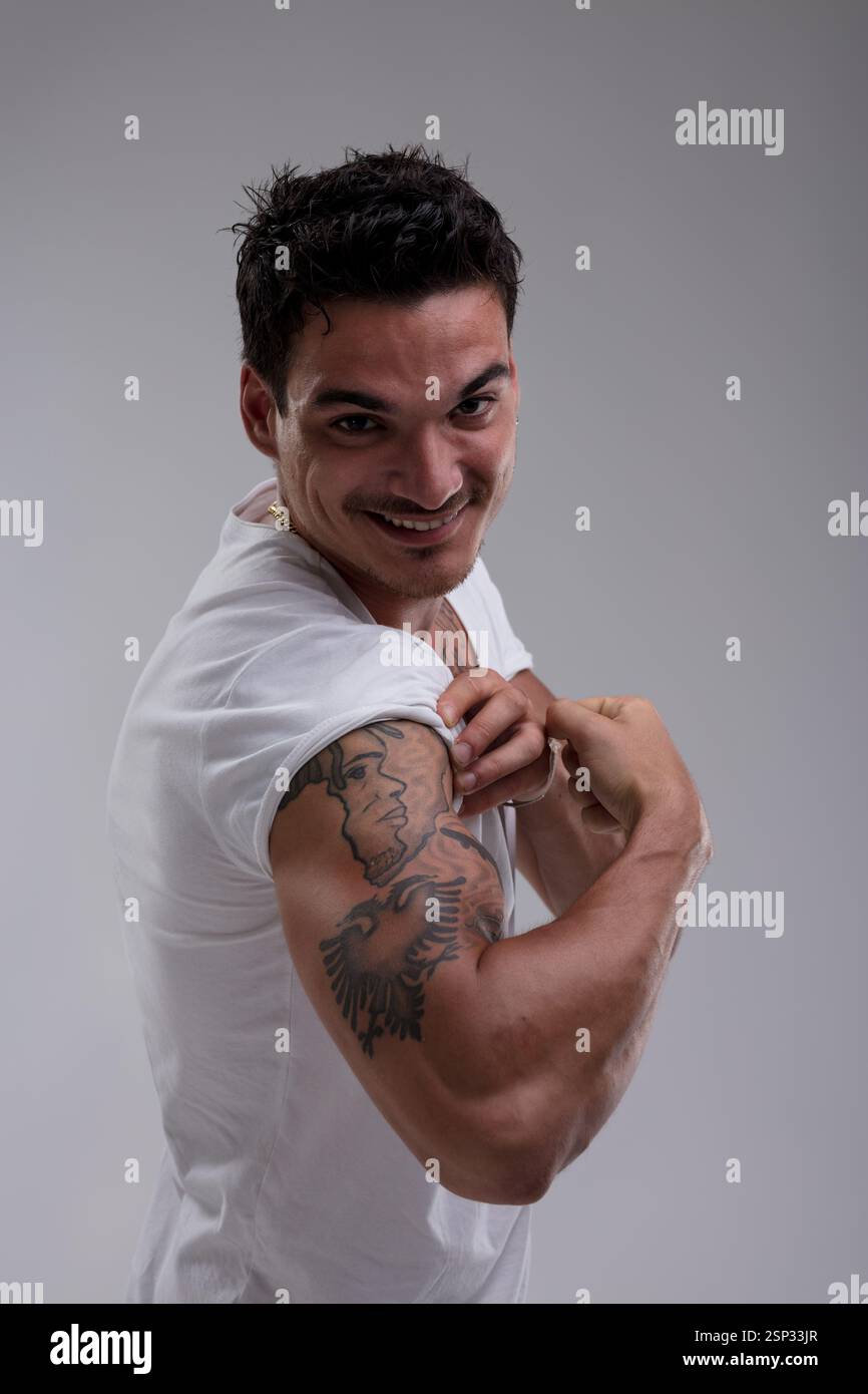 Young muscular man pulling up his sleeve to reveal a vibrant tattoo on ...