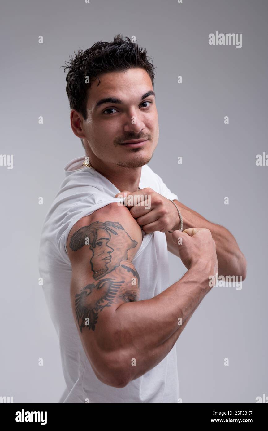 Young muscular man pulling up his white t-shirt, revealing a striking ...