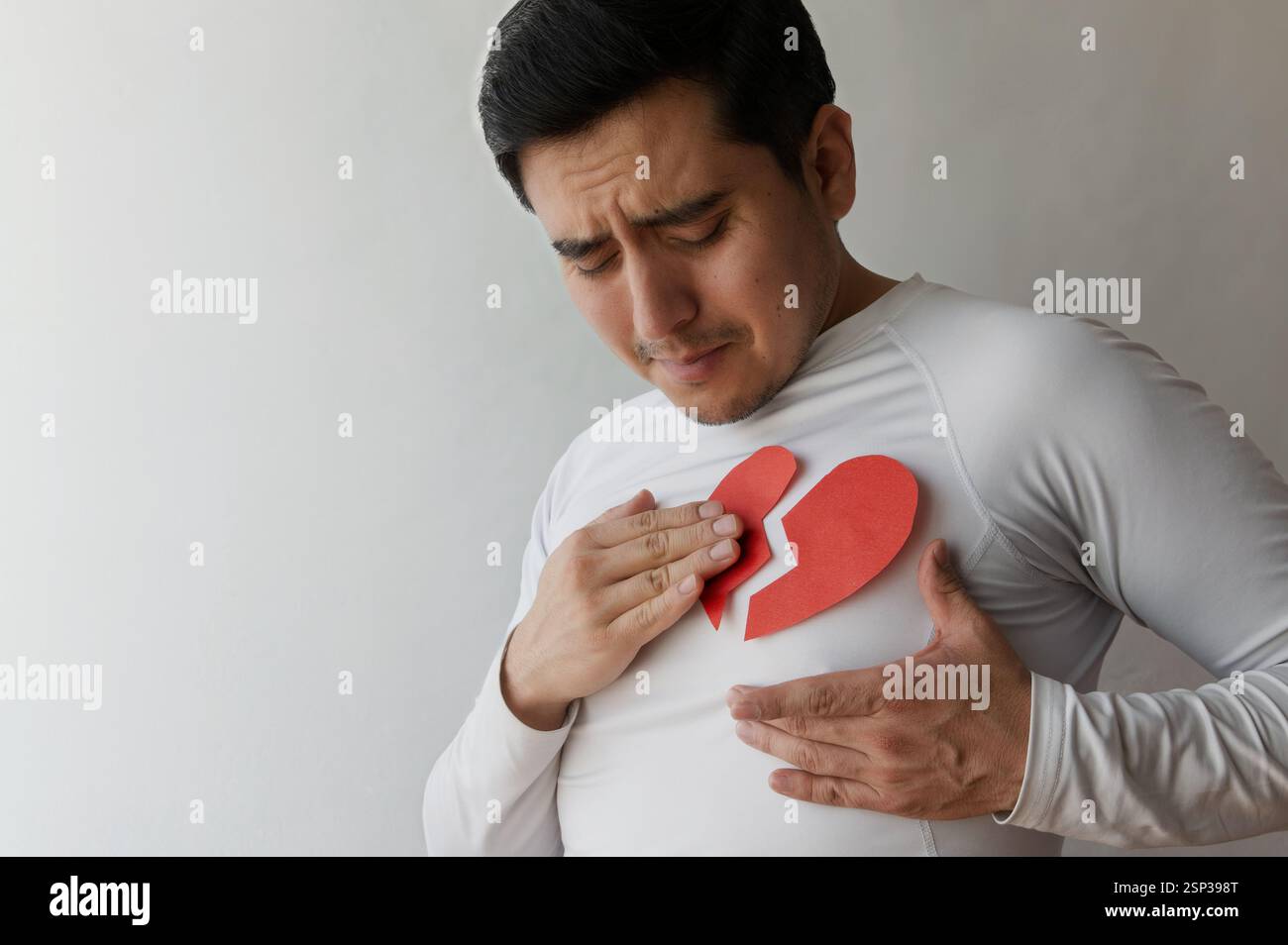 A man in a white long-sleeve shirt stands against a light background ...