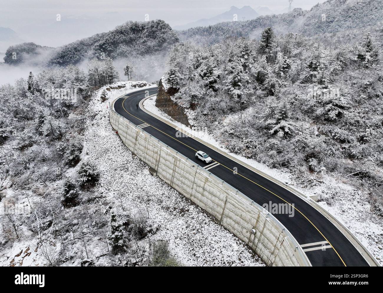 Aerial photo shows the scenery of a winding road after snow in Luojia ...