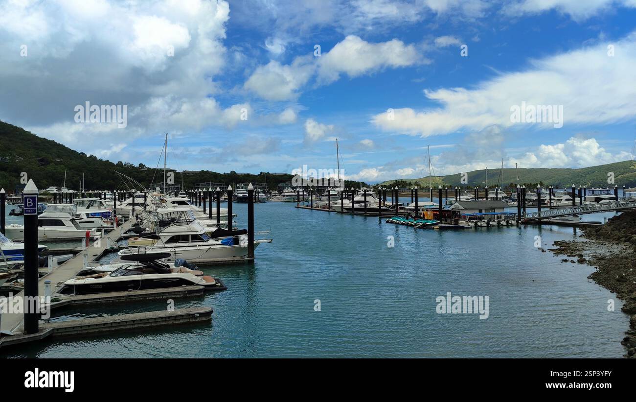 Hamilton Island marina. Several boats docked. Clear blue sky with white ...