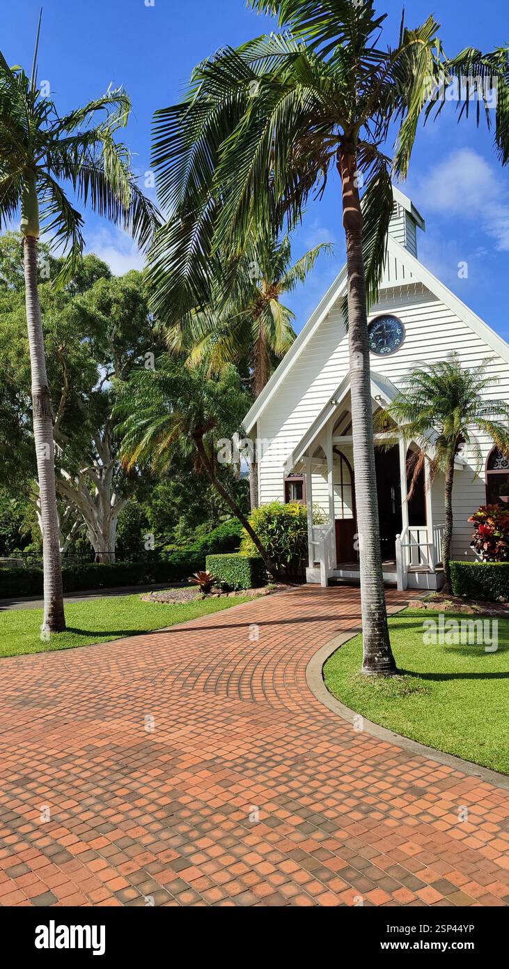 All Saints Chapel, a white church with a brick driveway flanked by palm ...