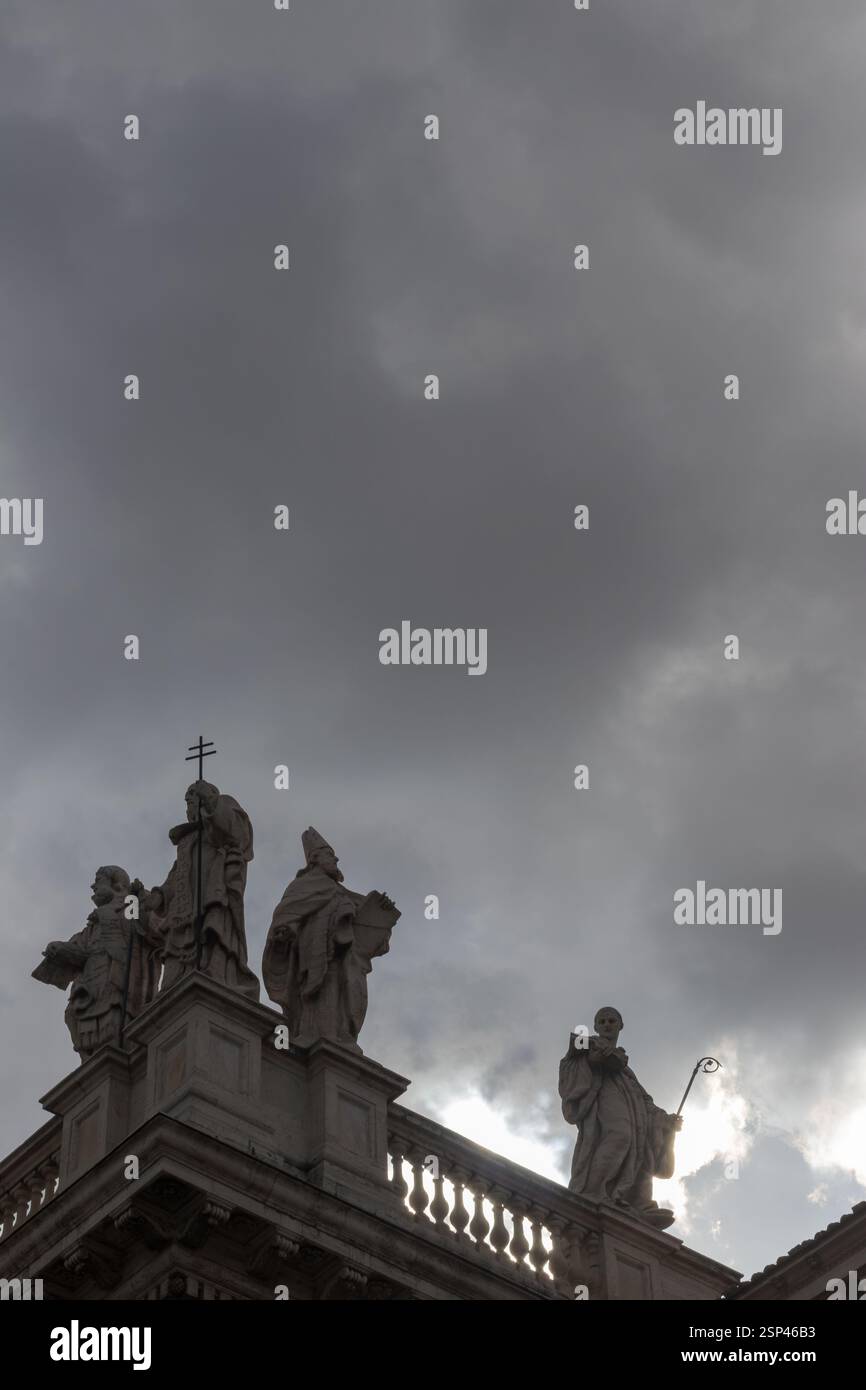 Historic stone statues atop an architectural building with a cloudy sky ...