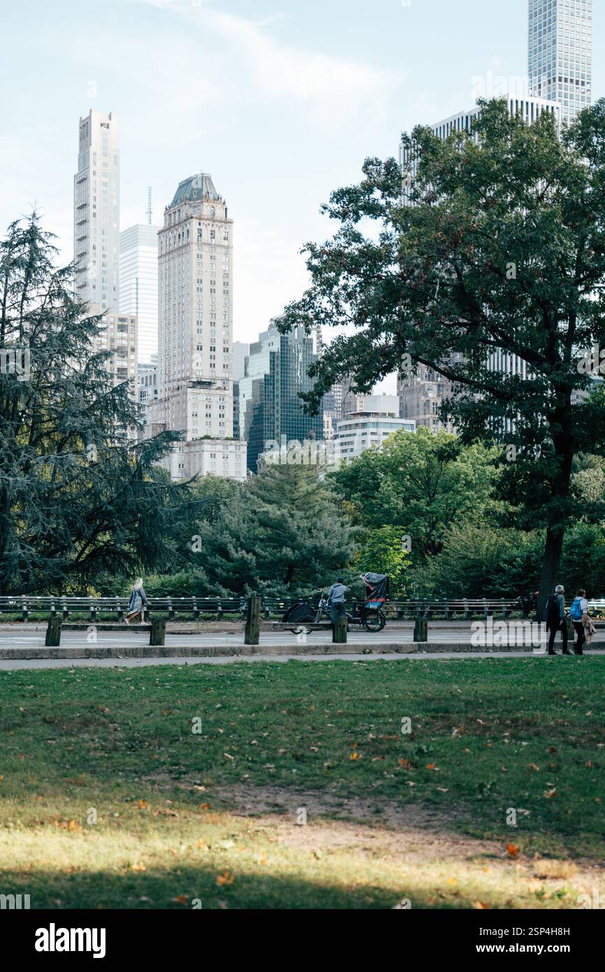 Visitors stroll through Central Park enjoying a sunny September day. The city skyline towers in ...