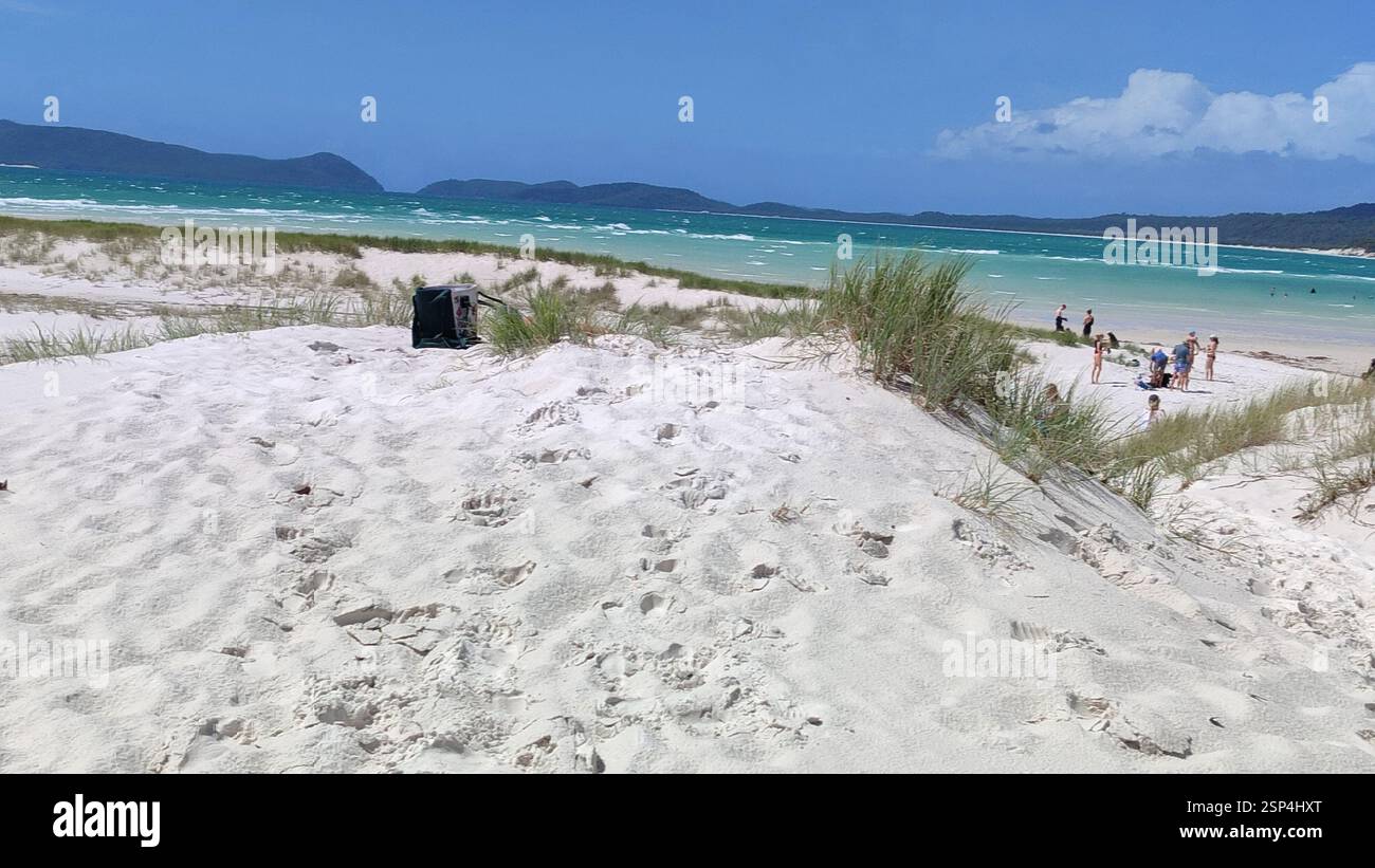 The photo captures people enjoying a day at Hamilton Island's beach ...