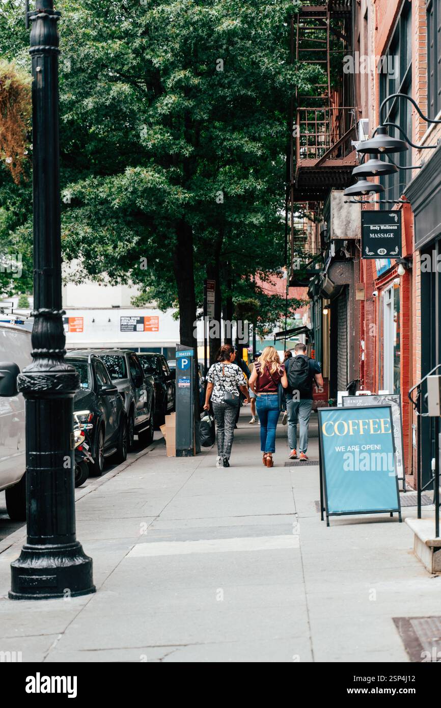 Three individuals walk side by side on a busy street in New York City ...