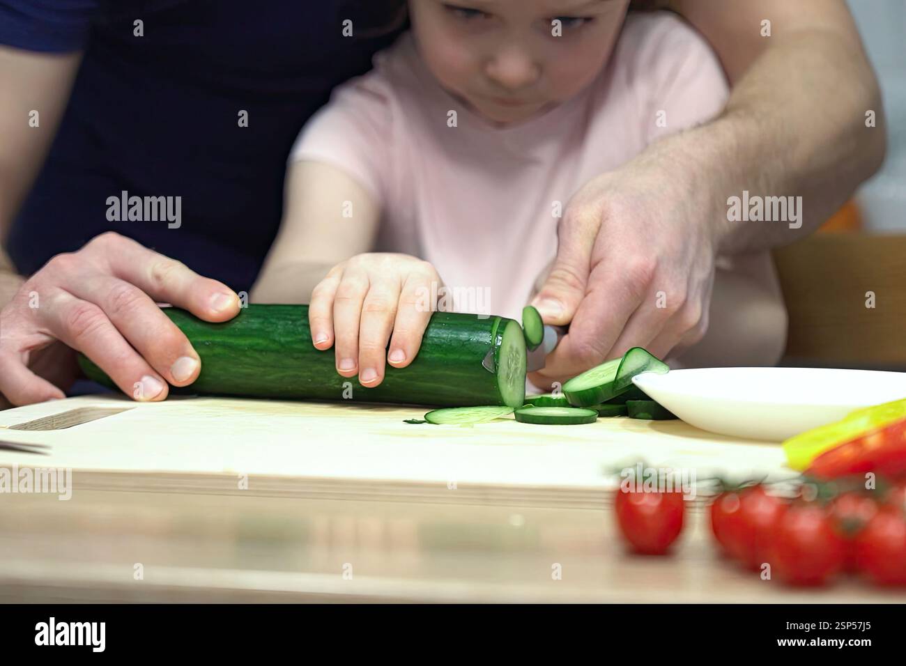 The father teaches his daughter to cook by chopping fresh vegetables ...