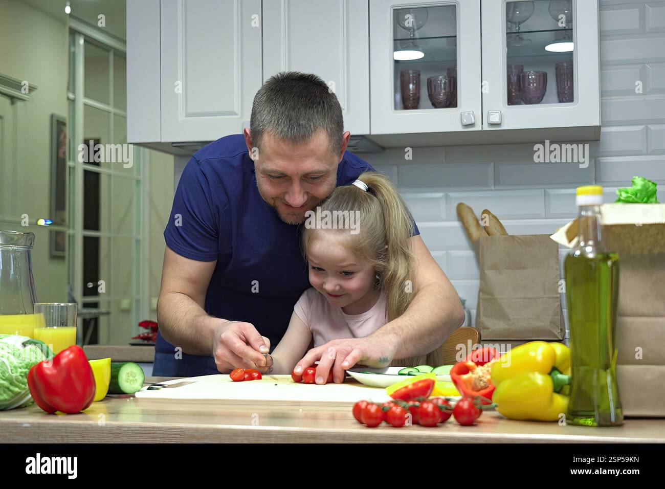 Family dinner: dad teaches his daughter to cook by chopping vegetables ...