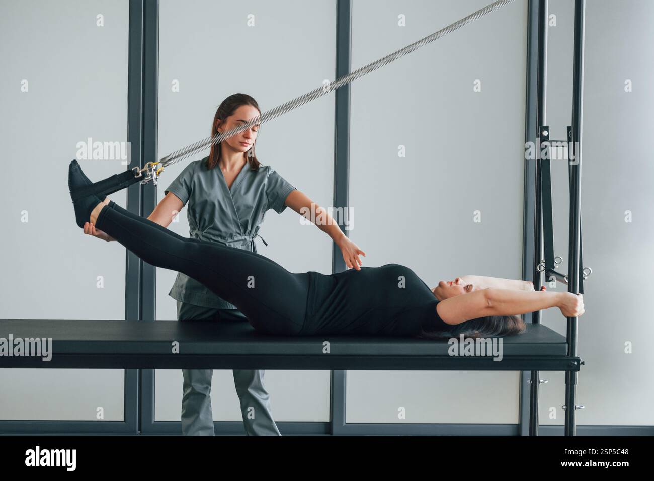 Legs is on the stretching cable. Woman is in health center getting help ...