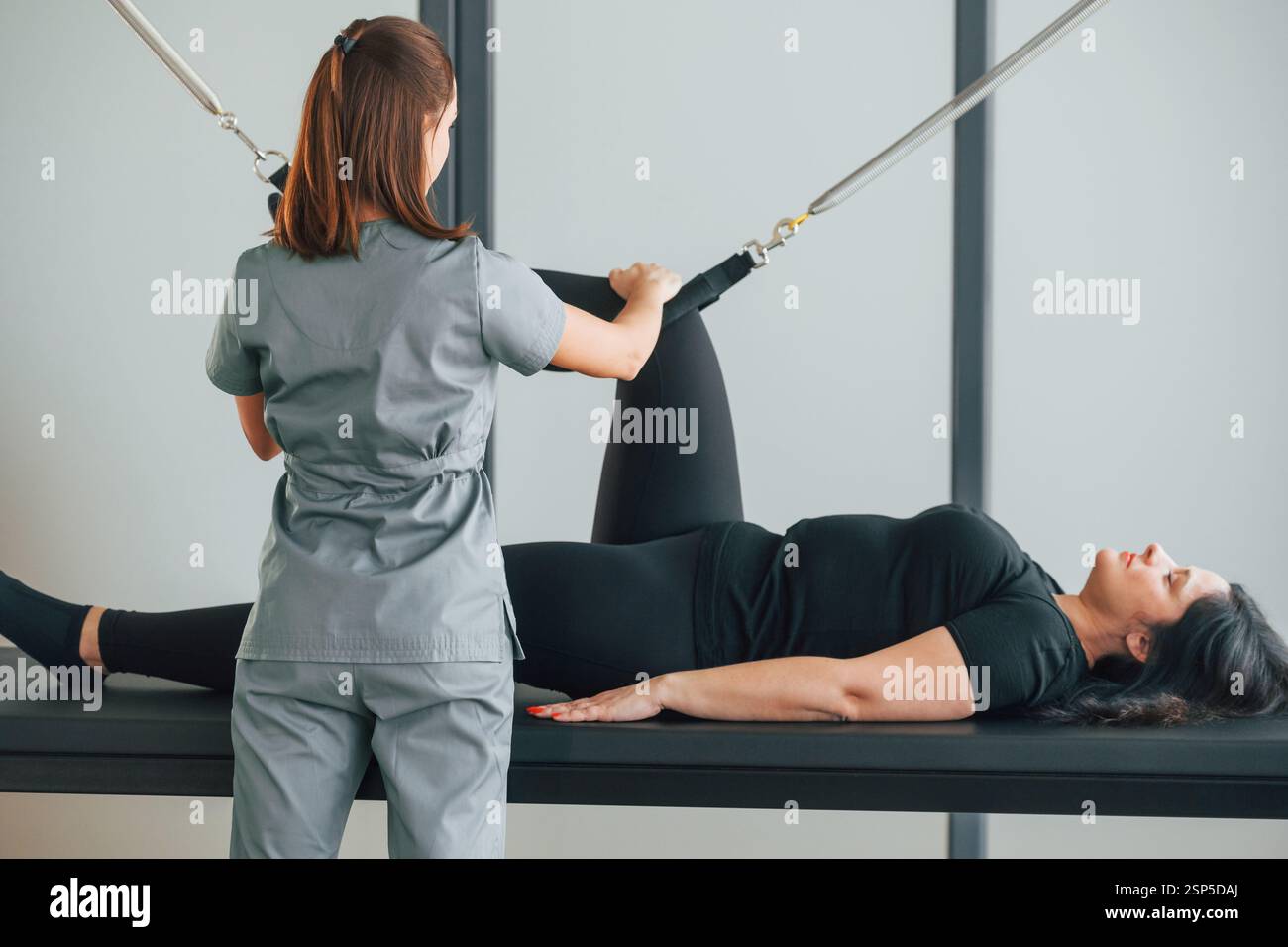 Legs is on the stretching cable. Woman is in health center getting help ...