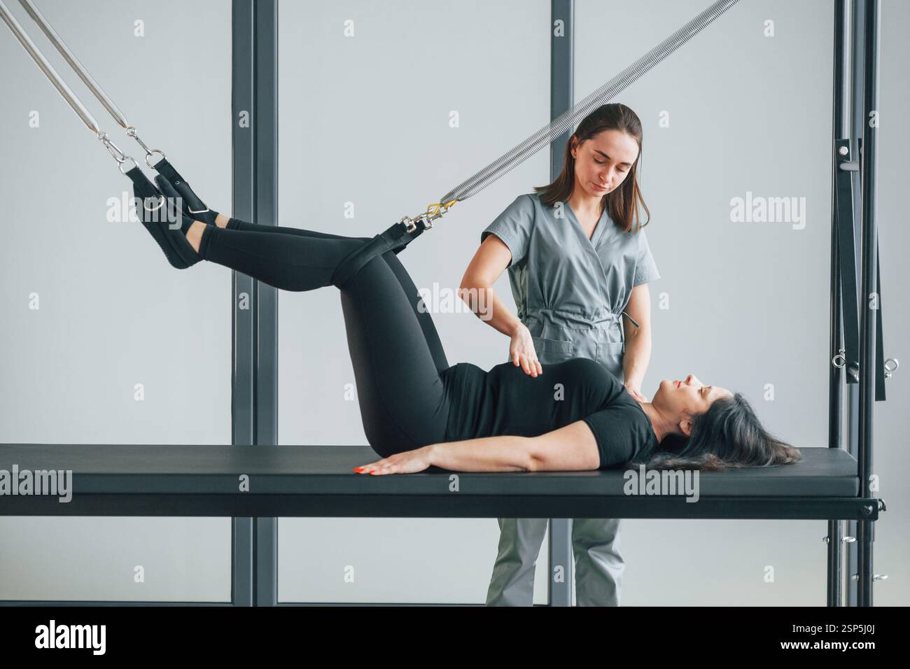 Legs is on the stretching cable. Woman is in health center getting help ...